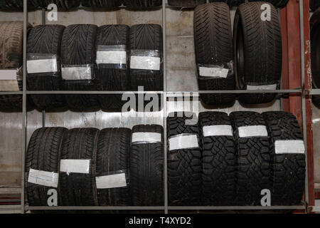 A large number of car wheels with tires stored vertically in racks for ...