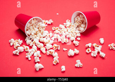 Fresh salty pop corn spilled out of a carton container, red color ...