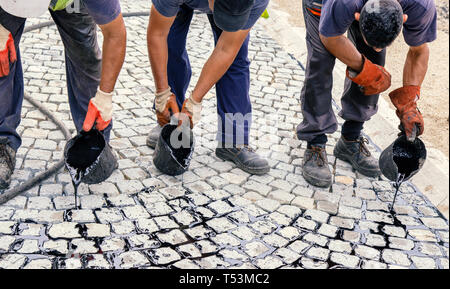 Worker pouring bitumen to apply the joint of road. Traditional pitch ...