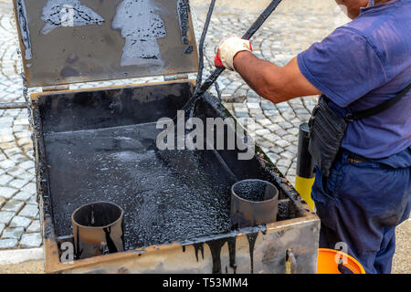Worker pouring bitumen to apply the joint of road. Traditional pitch ...