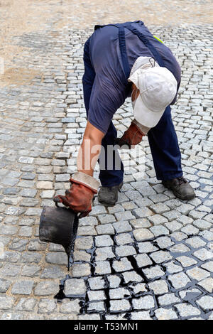 Worker pouring bitumen to apply the joint of road. Traditional pitch ...