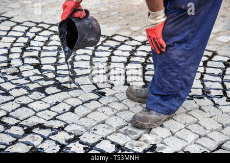 Worker pouring bitumen to apply the joint of road. Traditional pitch ...