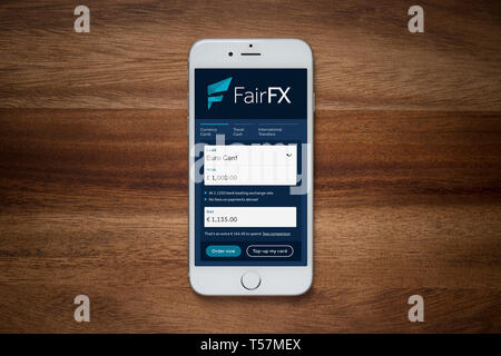 An iPhone showing the FairFX website rests on a yellow background table ...