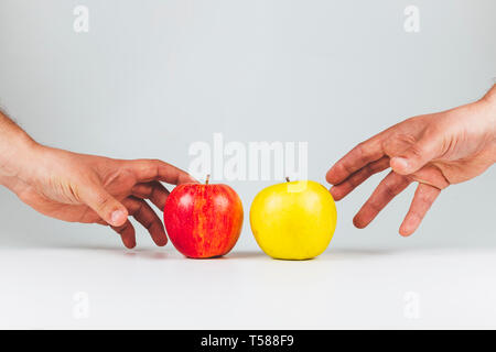 Two hands hold a fresh red tomato and a yellow bell pepper. The setting ...