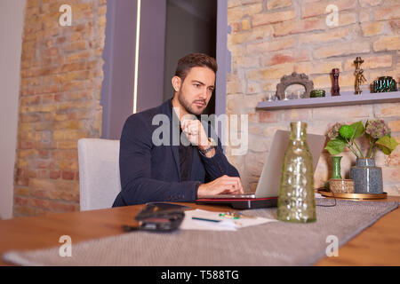 Young handsome businessman thinking while using phone Stock Photo - Alamy