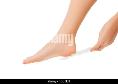 woman touching with feather to her smooth foot. Spa and foot care ...
