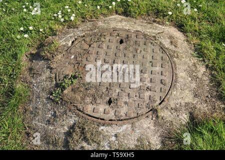 Drain cover embedded in textured black surface during bright daylight ...