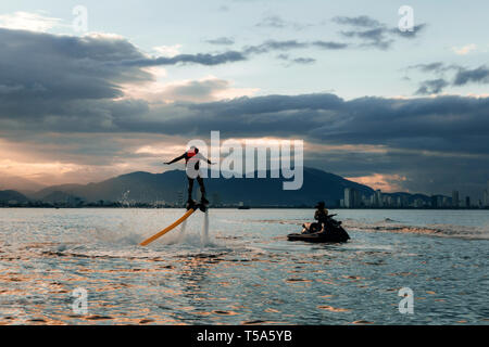 Silhouette of a fly board rider at sea and Parasailing in blue sky ...