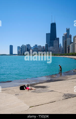 People sun tan on the Lakefront Trail on the North Side as a haze of ...