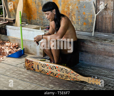 Orang Ulu tribal man making a sape (traditional lute), Sarawak Cultural ...