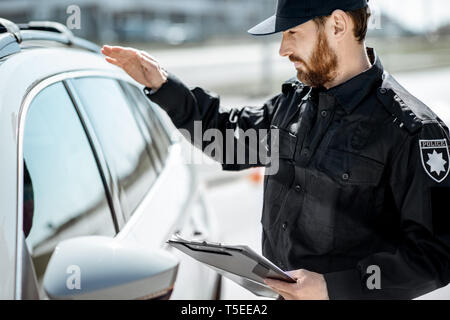Policeman knocking at the window to a car driver, stopping the car for ...