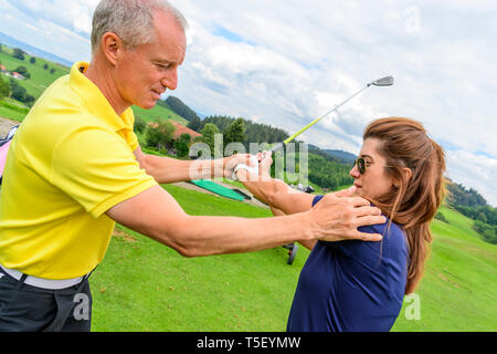 Golf players practising with golf pro on drivingrange Stock Photo - Alamy