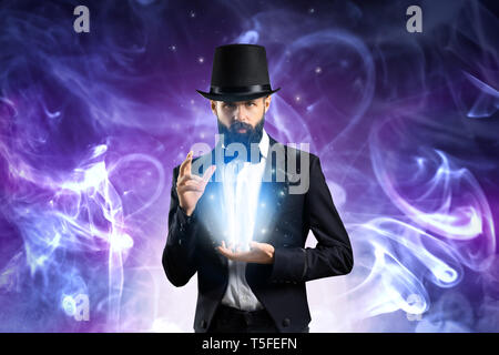 Magician showing tricks in smoke on dark background Stock Photo - Alamy