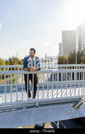 Man leaning on railing of footbridge Stock Photo - Alamy