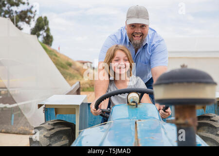Farmer showing his daughter, how to drive a tractor Stock Photo - Alamy