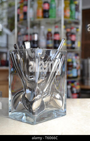 Close-up view to numerous teaspoons placed in a solid glass container ...