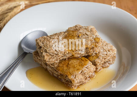Breakfast wheat cereal bars coated with honey in white bowl close up ...
