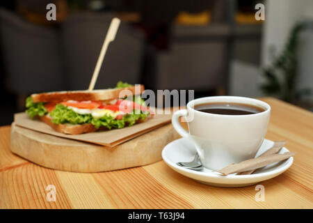 Fresh juicy sandwich with cup of hot coffee on wooden table with white ...