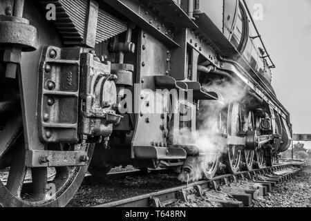 Low-angle side view of vintage, UK steam train moving along railway ...