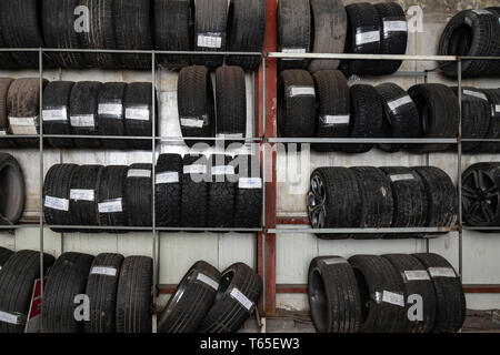 A large number of car wheels with tires stored vertically in racks for ...