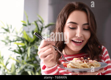 Young woman eating tasty pasta on white background Stock Photo - Alamy