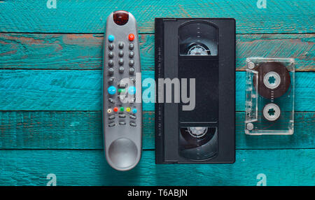 Video cassette, audio cassette, remote control on a blue wooden table ...