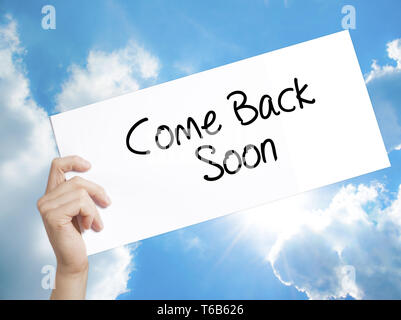 Come Back Soon Sign on white paper. Man Hand Holding Paper with text ...