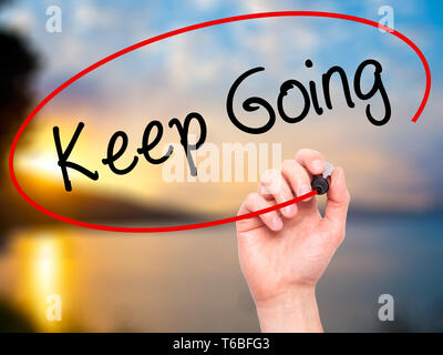 Man Hand writing Keep Going with black marker on visual screen ...