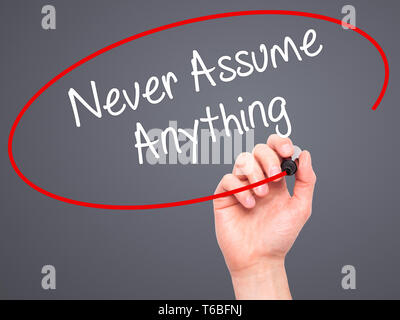 Man Hand writing Never Assume Anything with black marker on visual ...