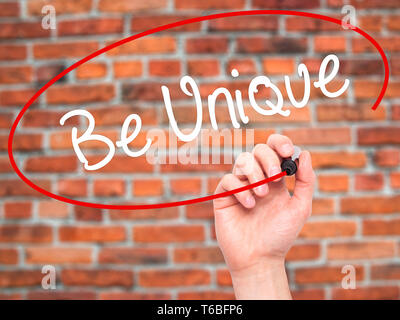 Man Hand writing Be Unique with black marker on visual screen. Isolated ...