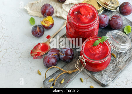 Wooden spoon with plum jam in a glass jar. Healthy food background ...