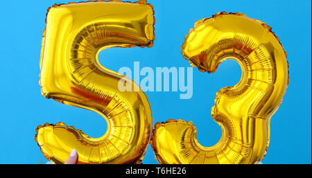Gold foil balloon number number 53 on a background of blue velvet ...