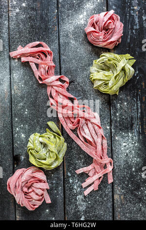 Homemade uncooked colorful tagliatelle pasta. Variety of colors. Dark ...