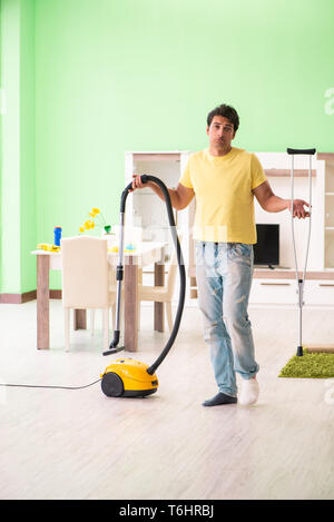 The injured man on crutches vacuum cleaning house Stock Photo - Alamy