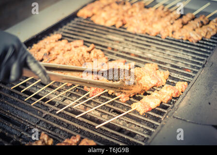Asian lady hand with glove turns skewer on grilling racks Stock Photo ...