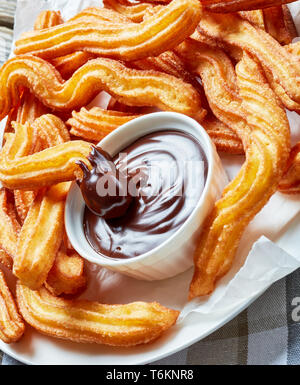 delicious deep fried churros served on a white plate on a wooden table ...