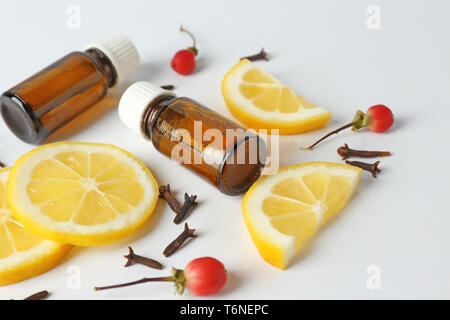 Composition with bottles of essential oil and sliced lemon on white ...