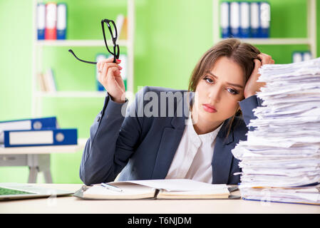 Young female employee very busy with ongoing paperwork in time ...