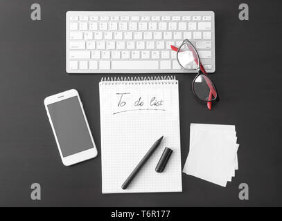 Empty to-do list with phone and computer keyboard on wooden background ...
