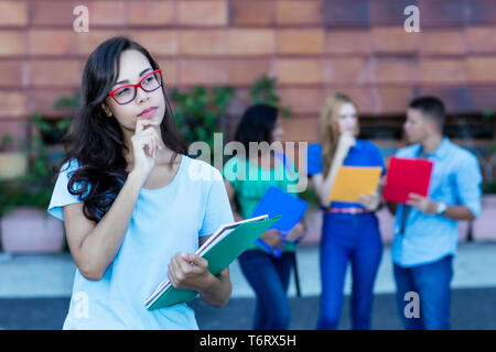 Nerdy female student with eyeglasses and group of international ...