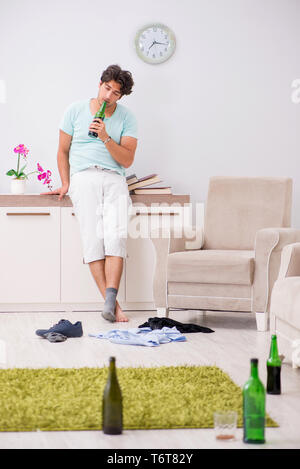 Young man with hangover after Birthday party putting bottle to his head ...