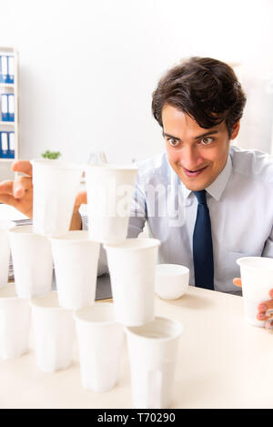 The young employee building pyramid from plastic cups Stock Photo - Alamy