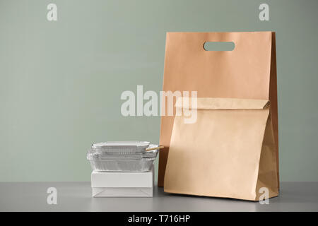 Different packages on table against color background. Food delivery ...