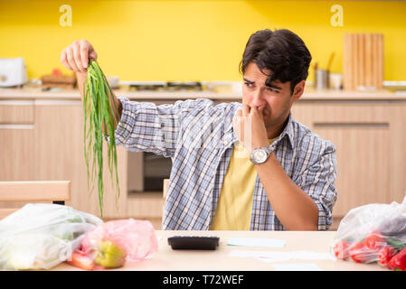 Young man calculating expences for vegetables in kitchen Stock Photo ...