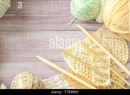 Knitting needles with unfinished clothes on color wooden background ...
