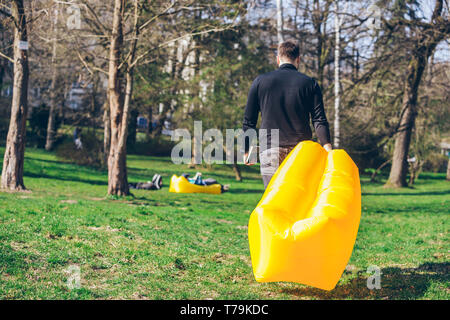 man walking with yellow inflatable mattress to place for reading book ...