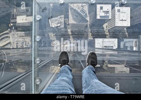 Hanging off the edge of the Willis Tower observation deck on a glass ...