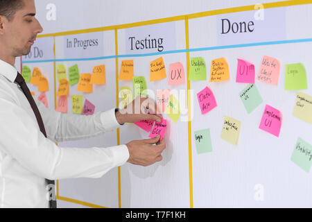 Man near scrum task board with stickers in office Stock Photo - Alamy