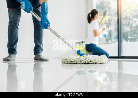 Young housekeeper cleaning floor mobbing holding mop and plastic bucket ...