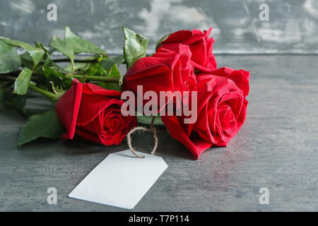 Beautiful roses with tag on grey background Stock Photo - Alamy